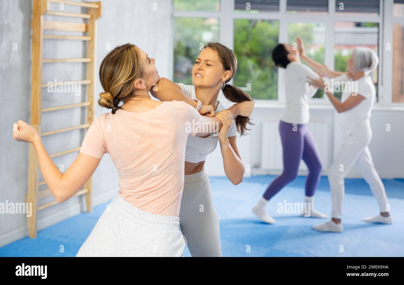 Woman and girl in gym perform basic elements of krav maga self-defense ...