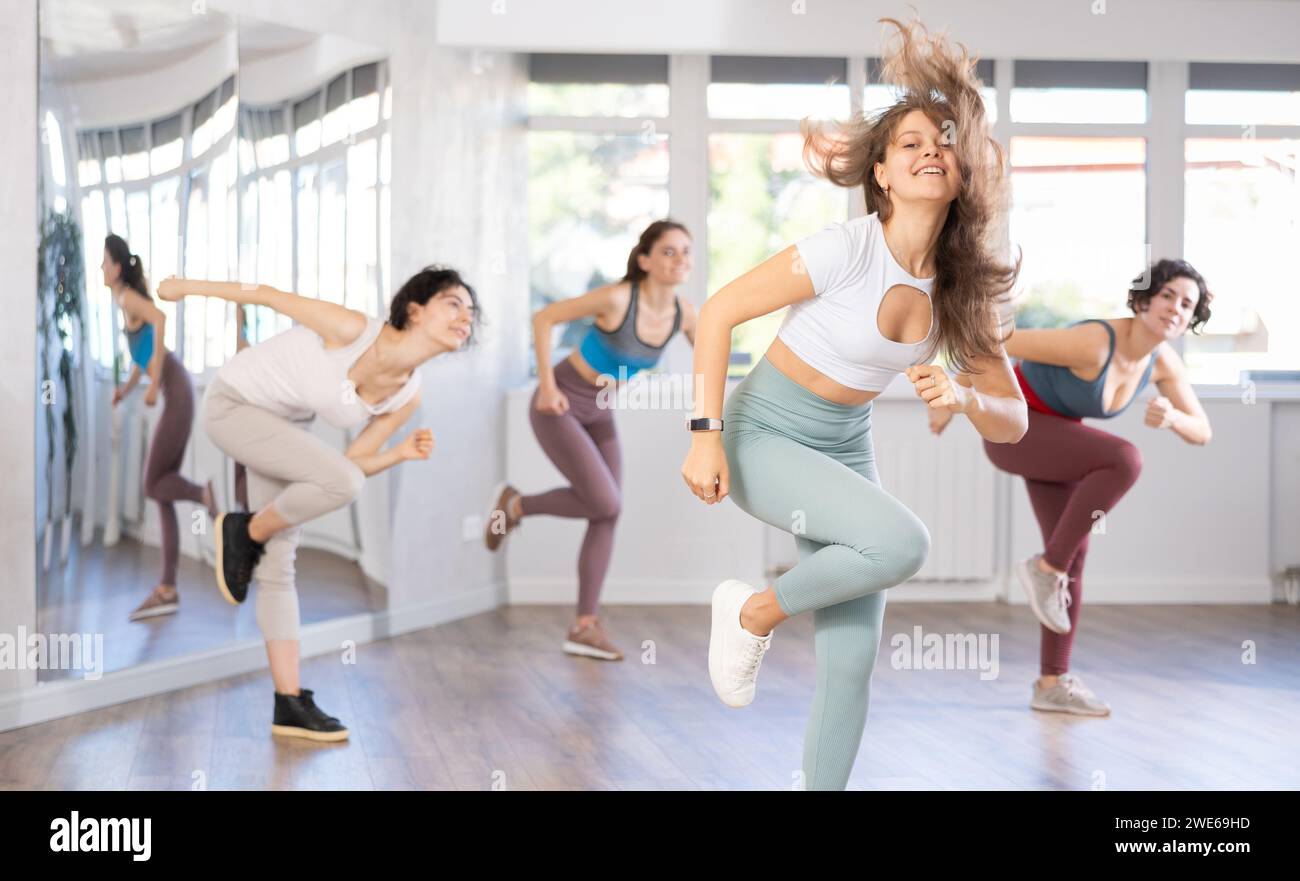 Young female teacher conducts modern dance lessons for group of girls ...