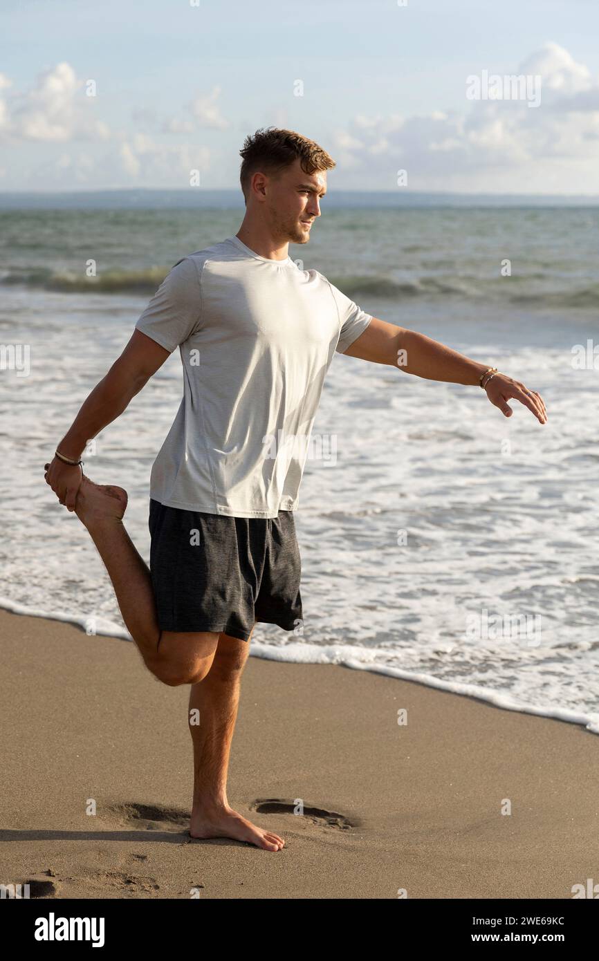 Young man stretching leg at beach Stock Photo - Alamy