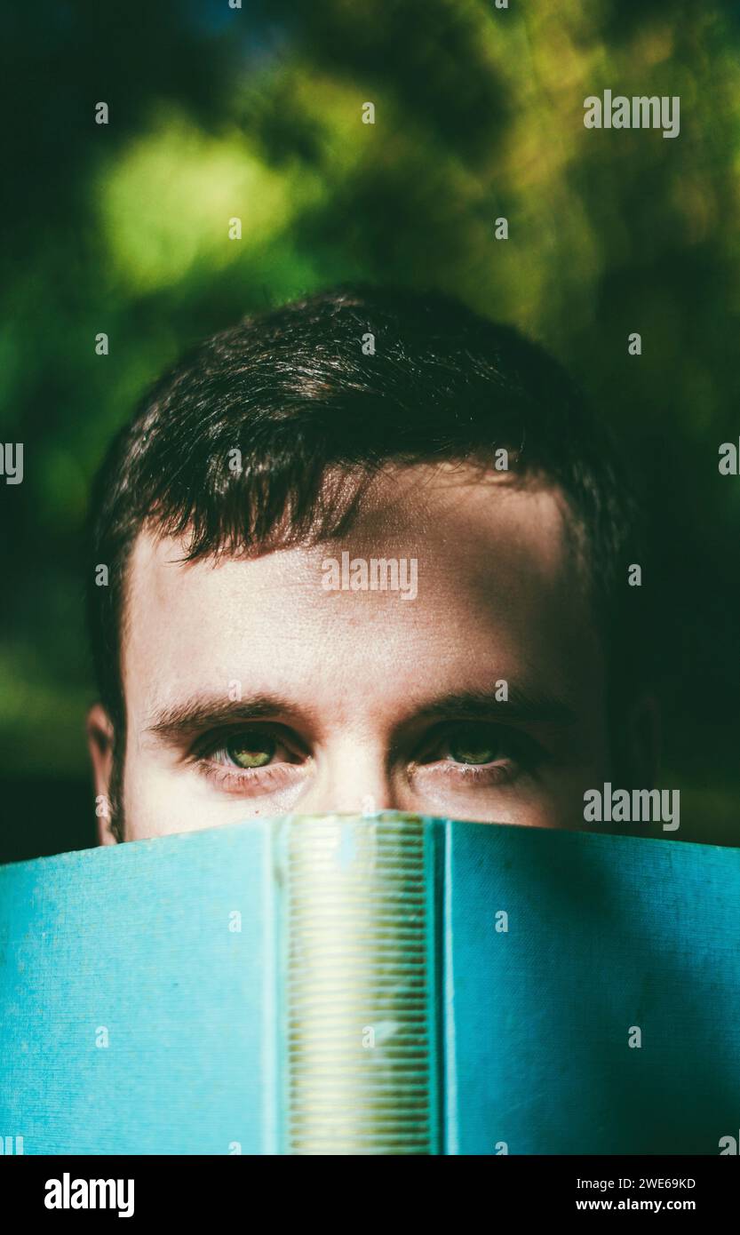 Man hiding face with book Stock Photo - Alamy