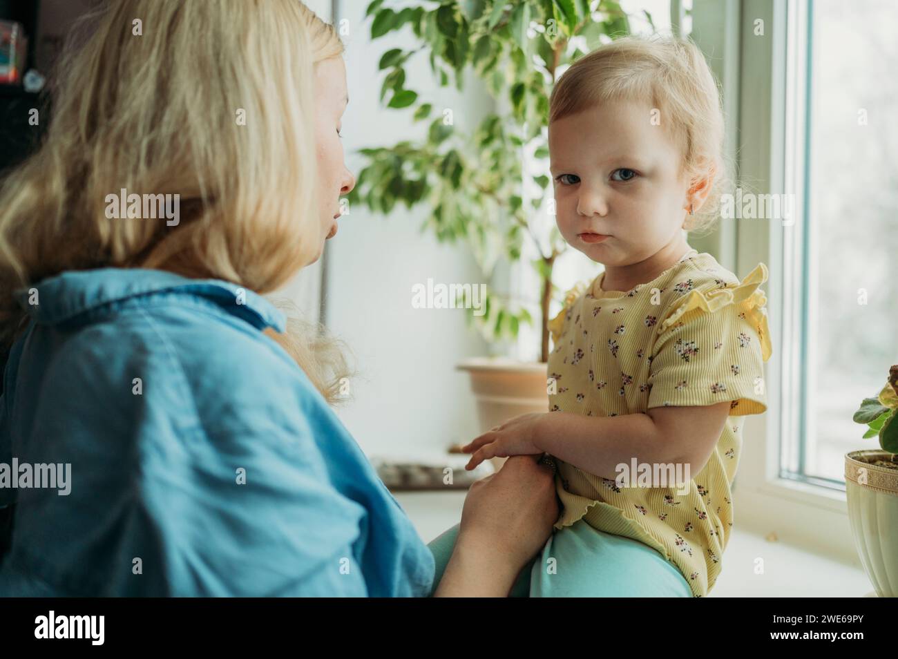 Mother talking to daughter near window at home Stock Photo - Alamy