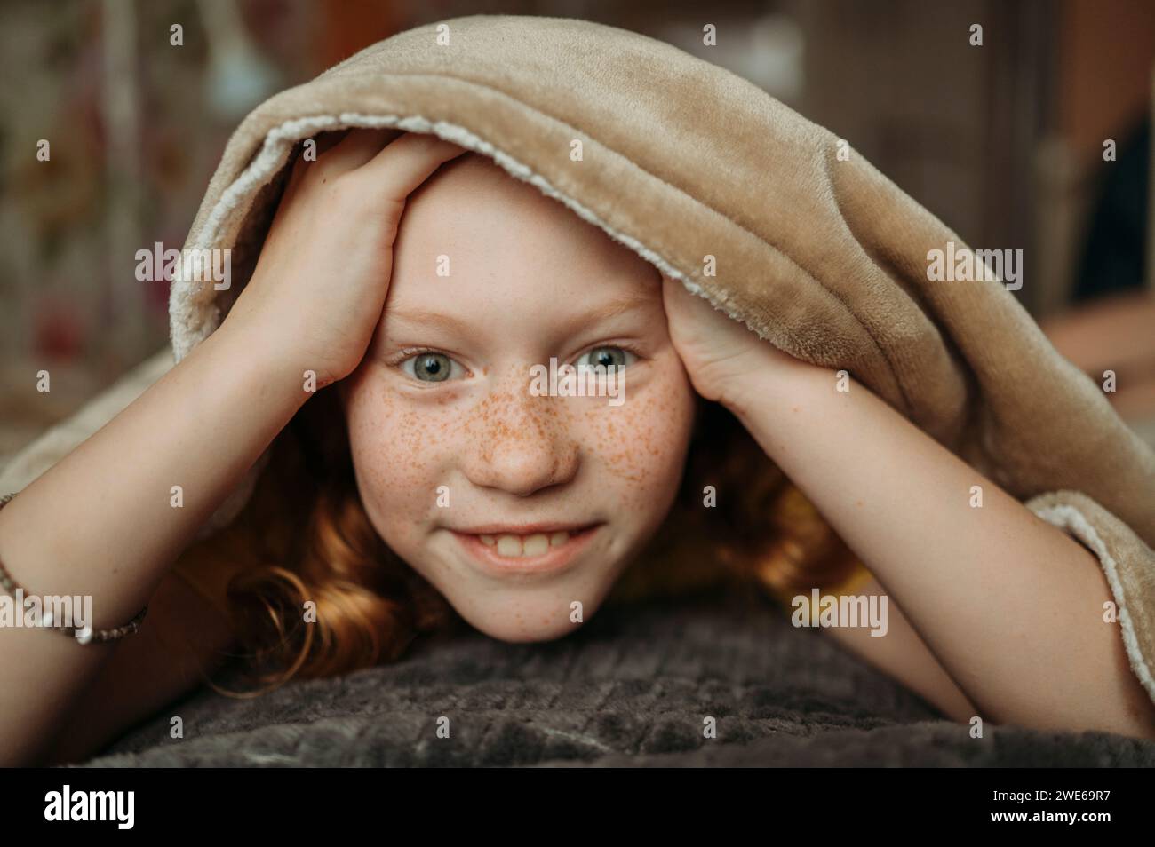Smiling girl under blanket on bed Stock Photo - Alamy