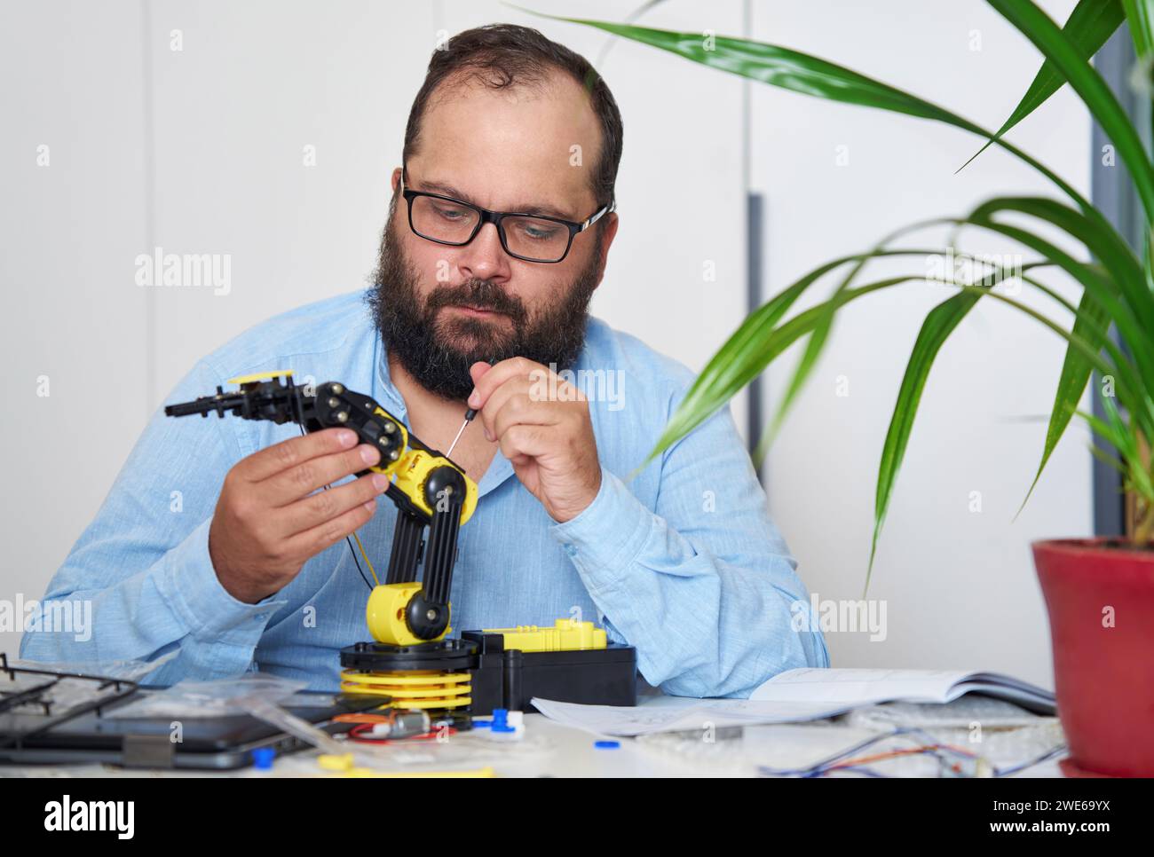 Engineer working on robotic arm at desk in office Stock Photo - Alamy