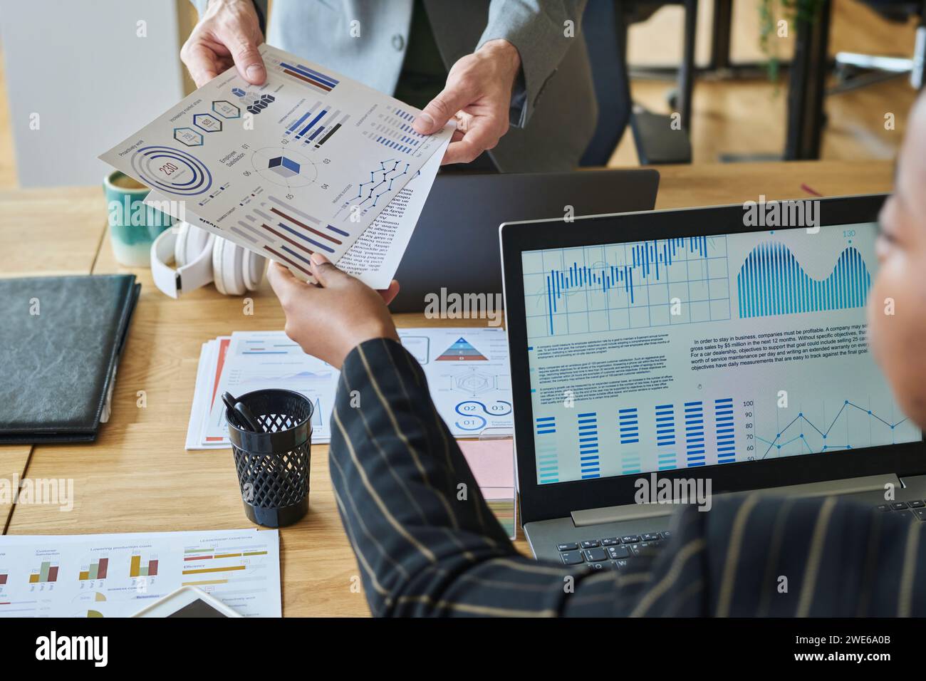 Businesswoman receiving chart and graph reports from coworker in office ...