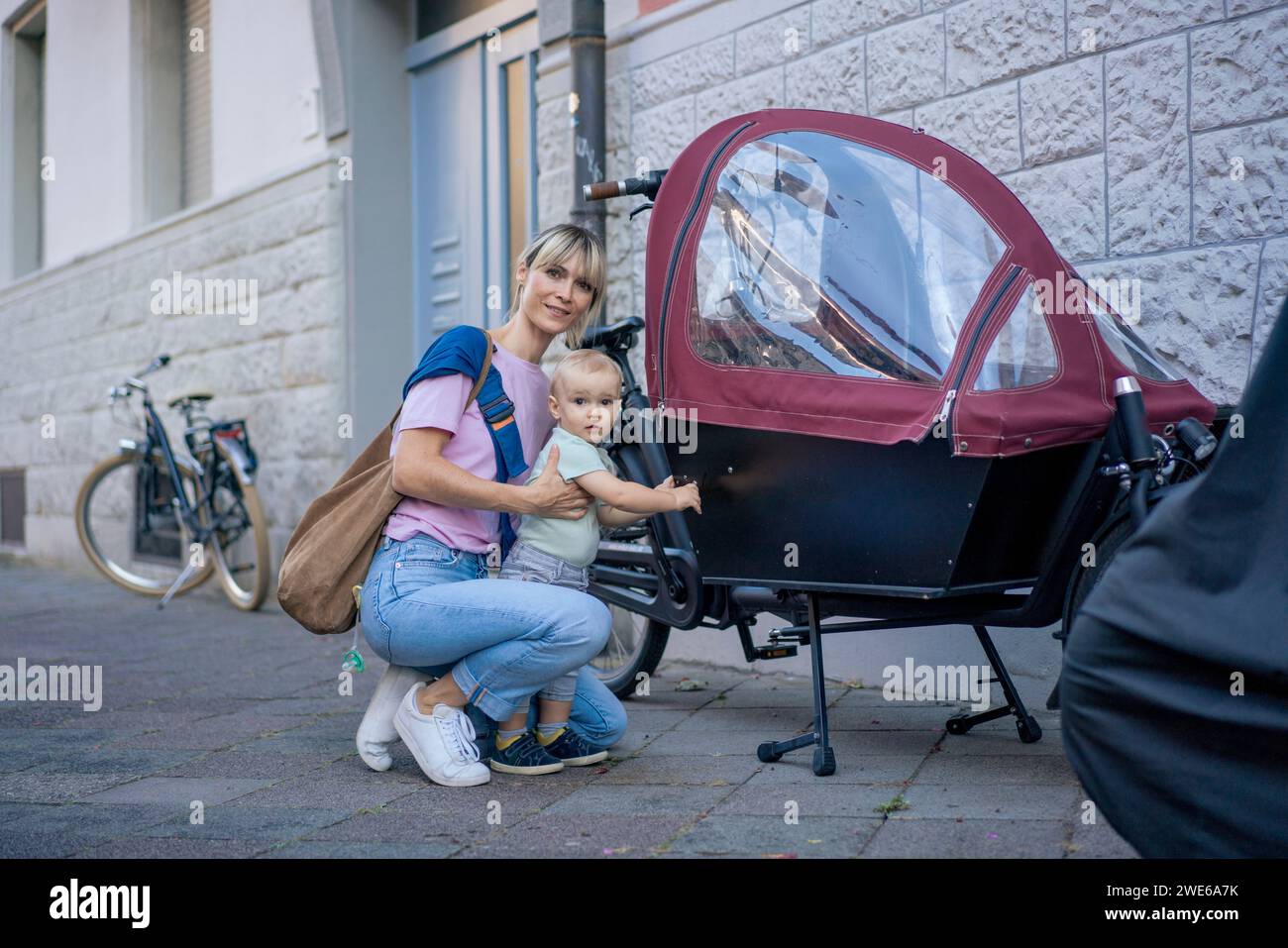 Mother crouching by son standing near cargo bike on sidewalk Stock ...
