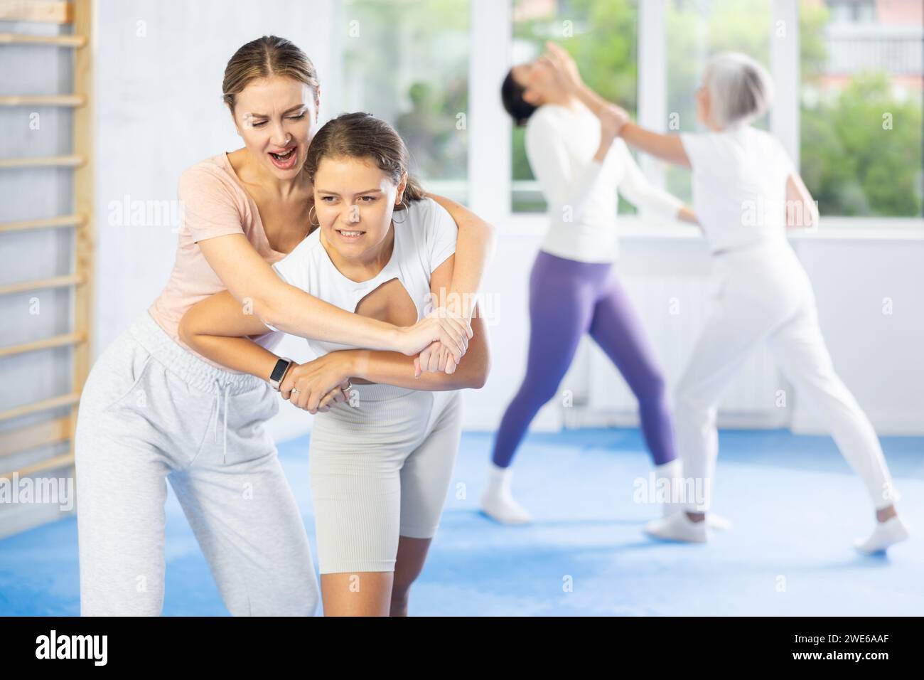 Woman and girl in gym perform basic elements of krav maga self-defense ...