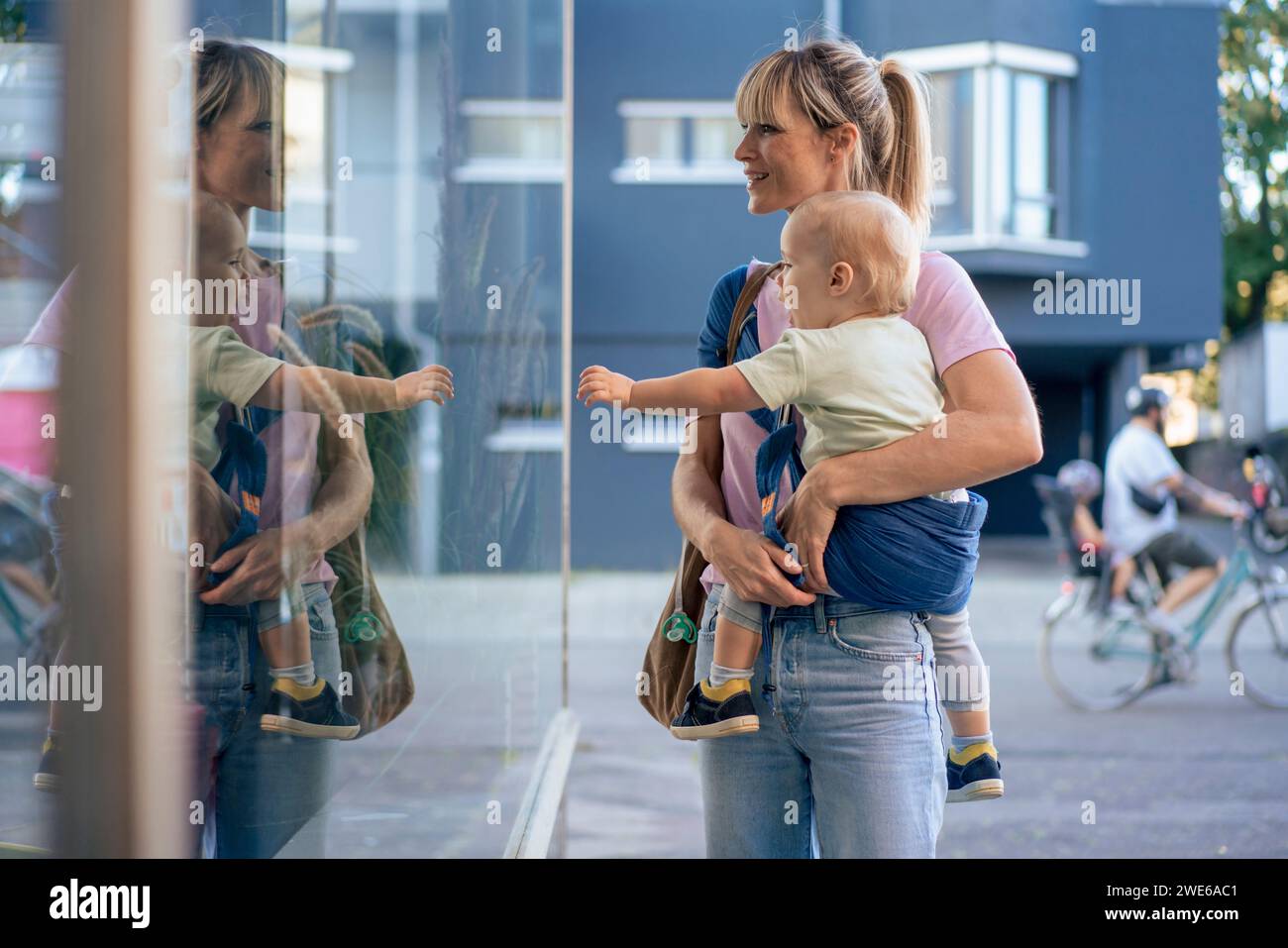 Mother doing window shopping with son in baby sling at street Stock ...