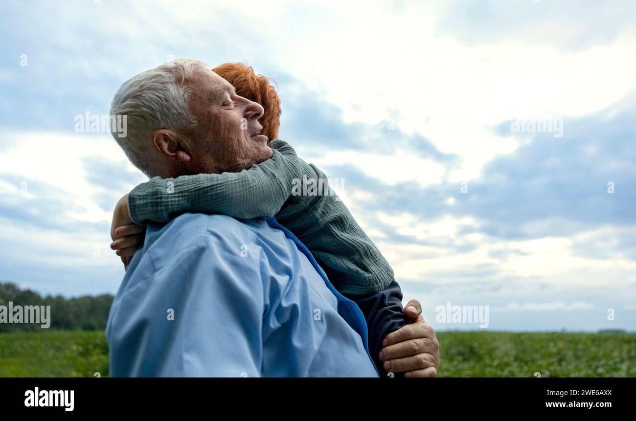 Boy hugging grandfather under cloudy sky at sunset Stock Photo - Alamy