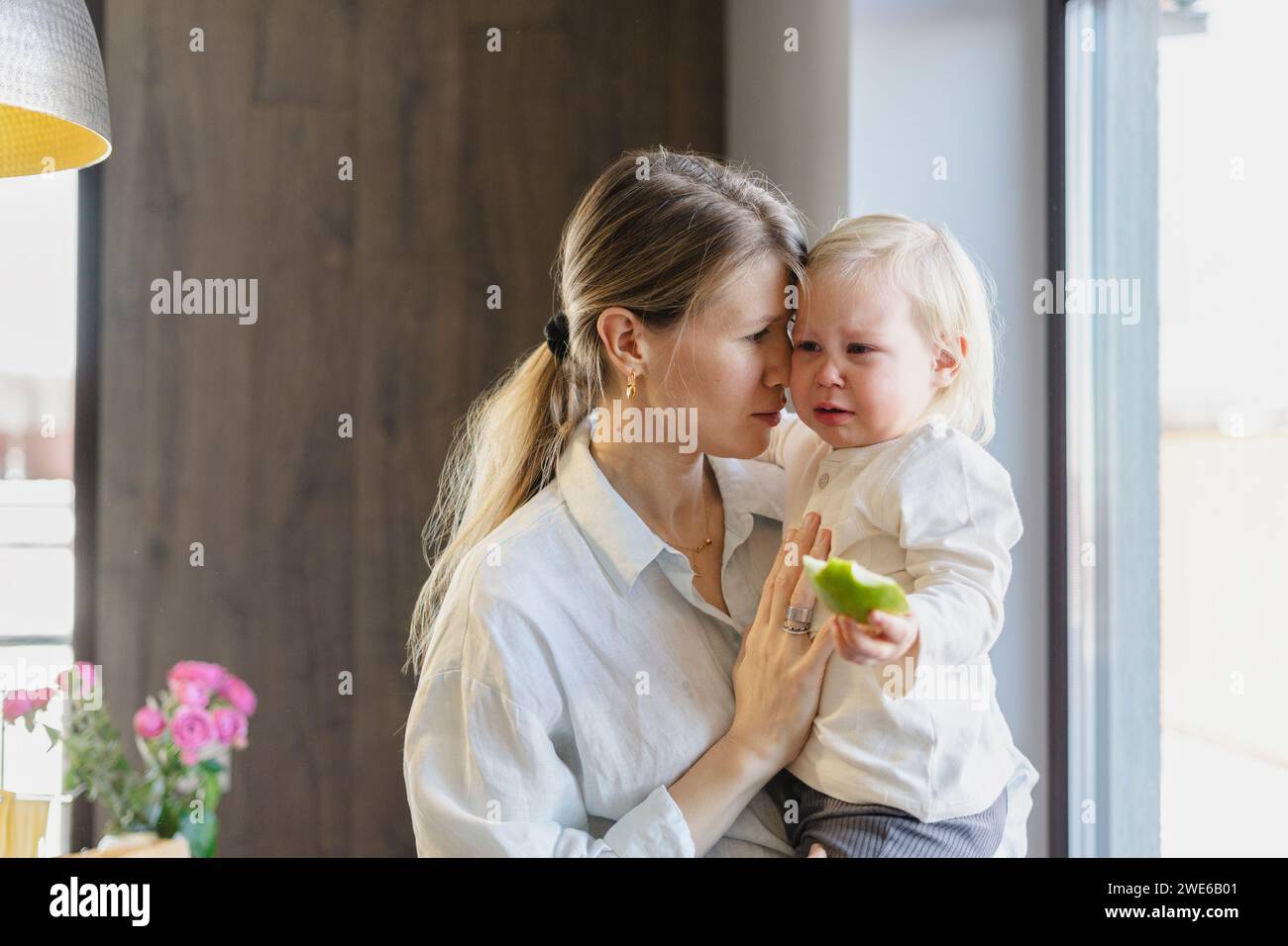 Mother consoling crying daughter near window at home Stock Photo - Alamy