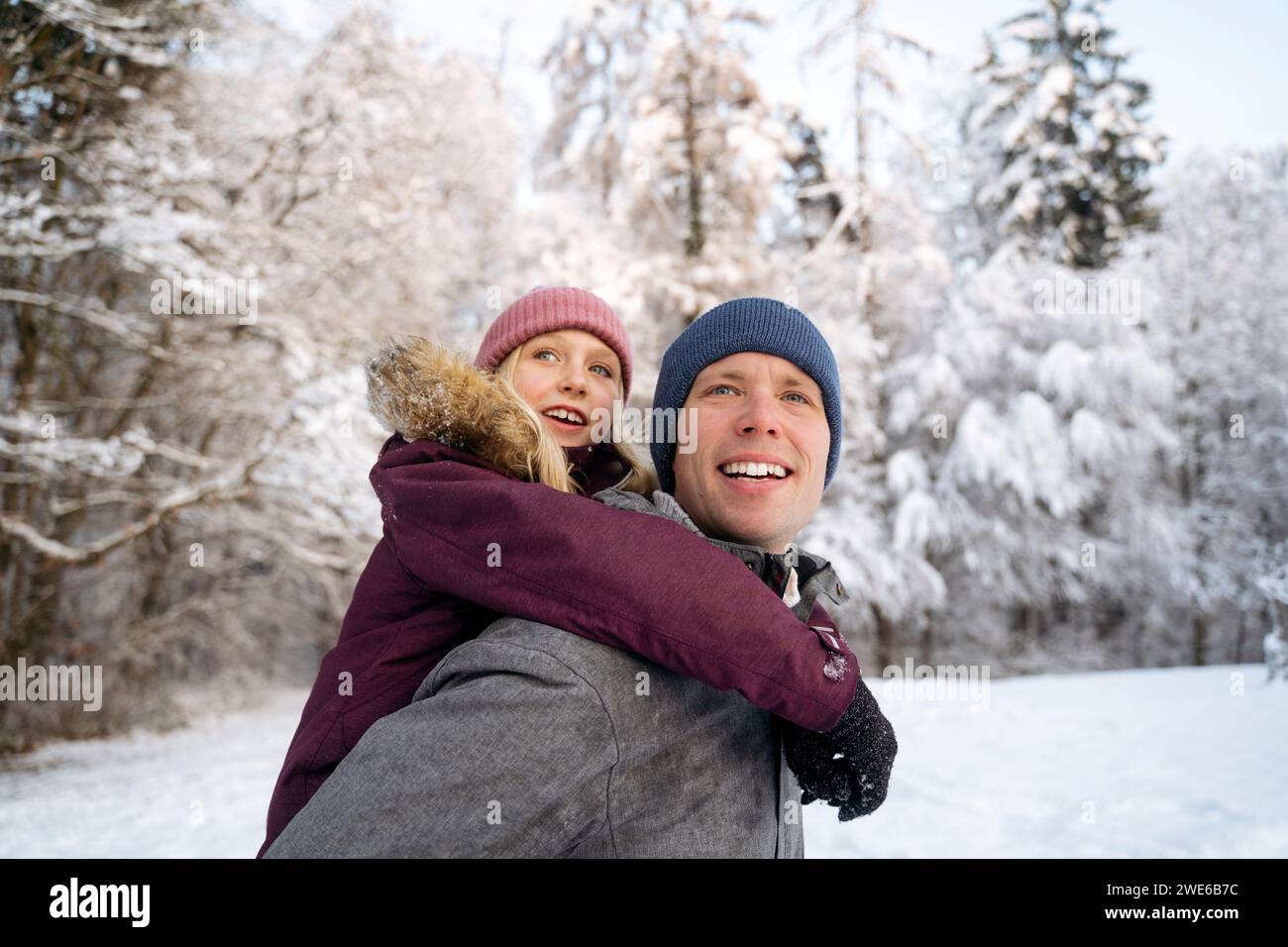 Smiling man giving piggyback ride to daughter at winter forest Stock ...