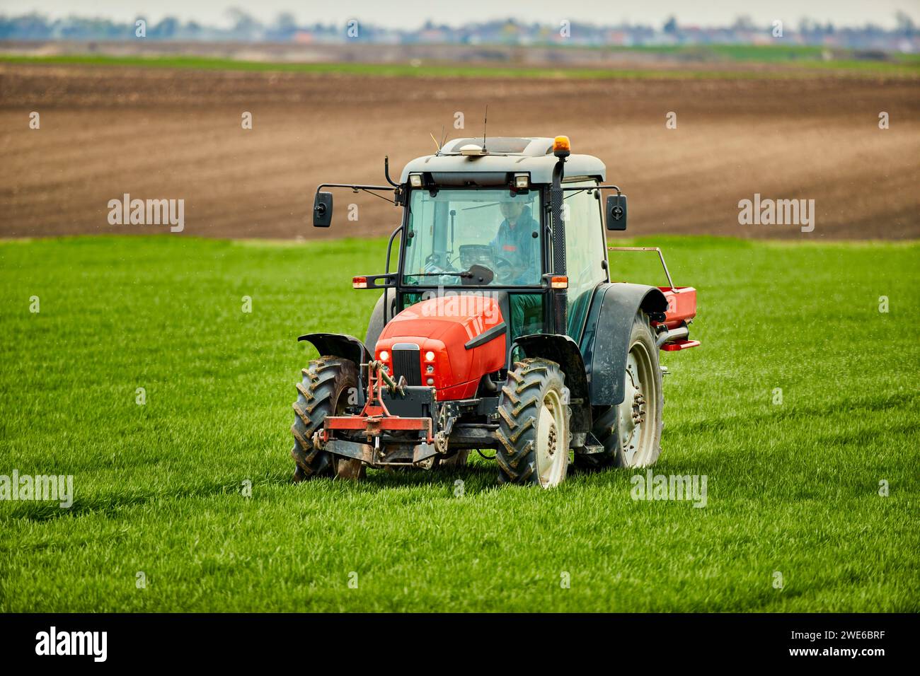 Young farmer in tractor fertilizing wheat field Stock Photo - Alamy