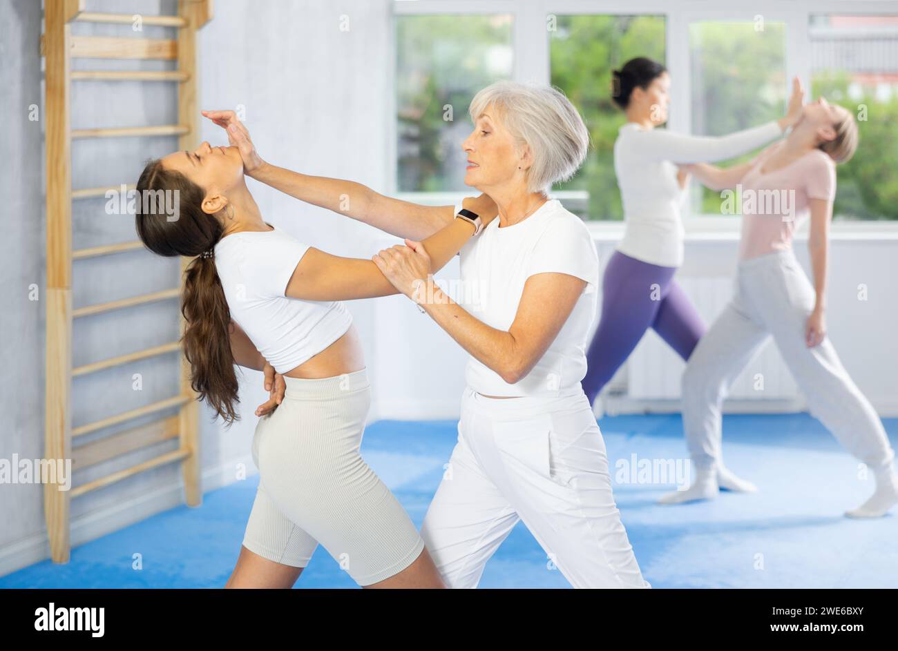 Woman and girl in gym perform basic elements of krav maga self-defense ...