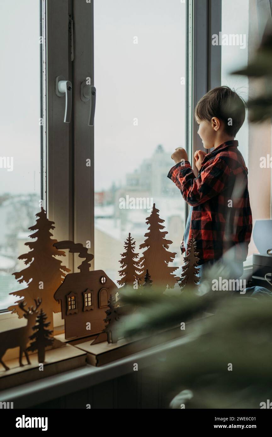 Boy looking through window christmas hi-res stock photography and ...