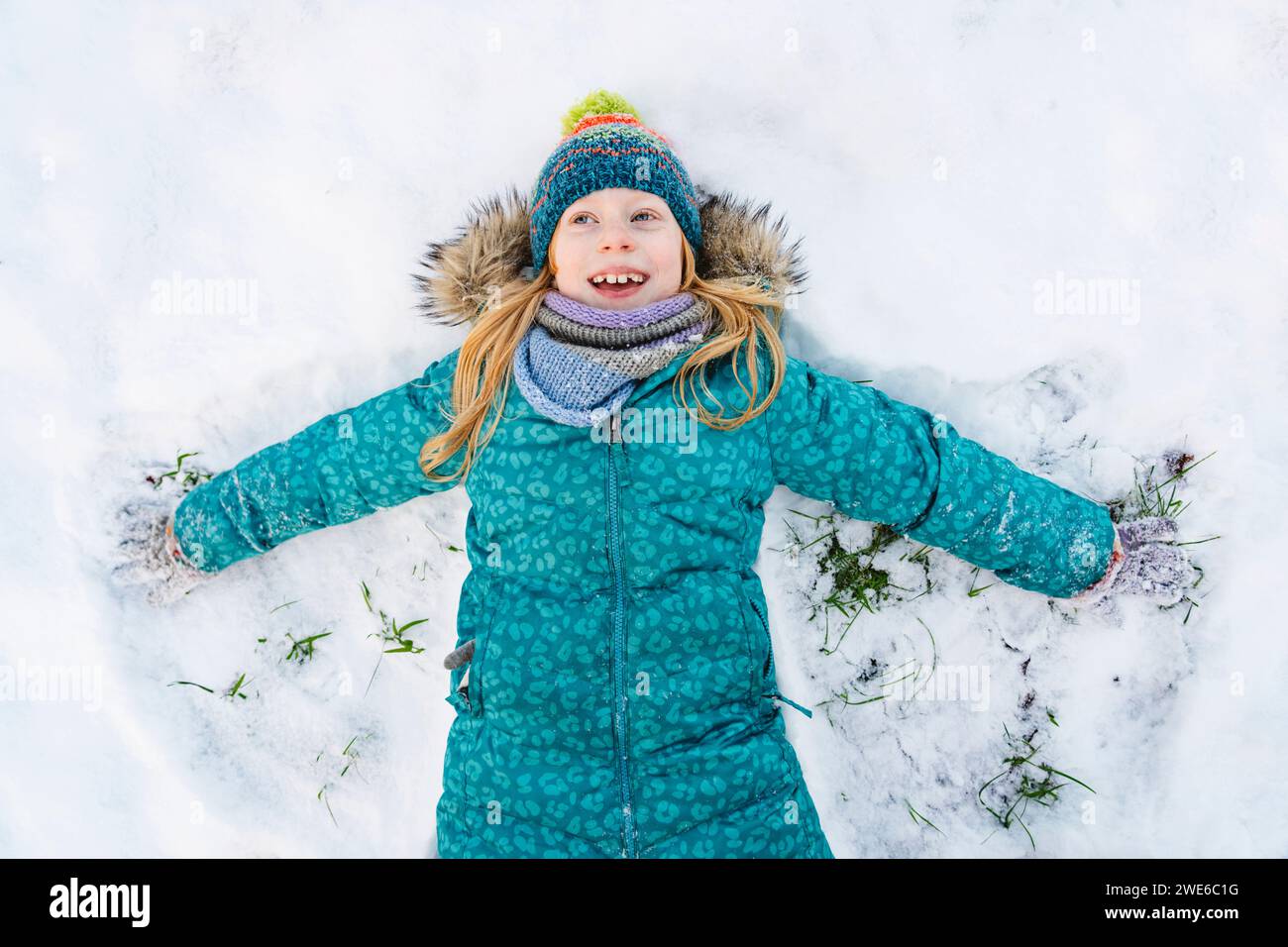 Happy girl lying on back and making snow angel Stock Photo - Alamy