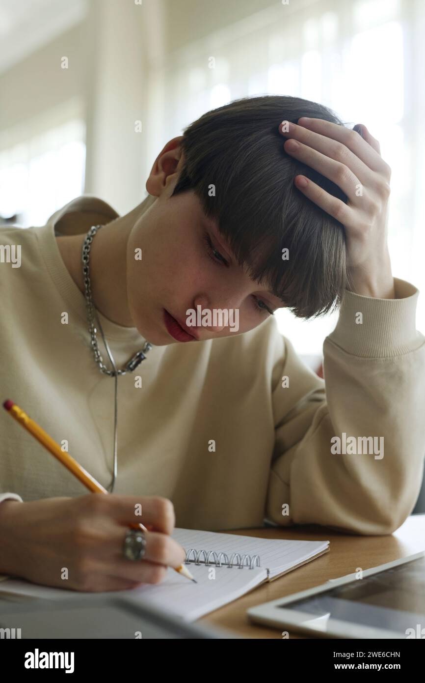 Student writing in book and studying at library Stock Photo - Alamy