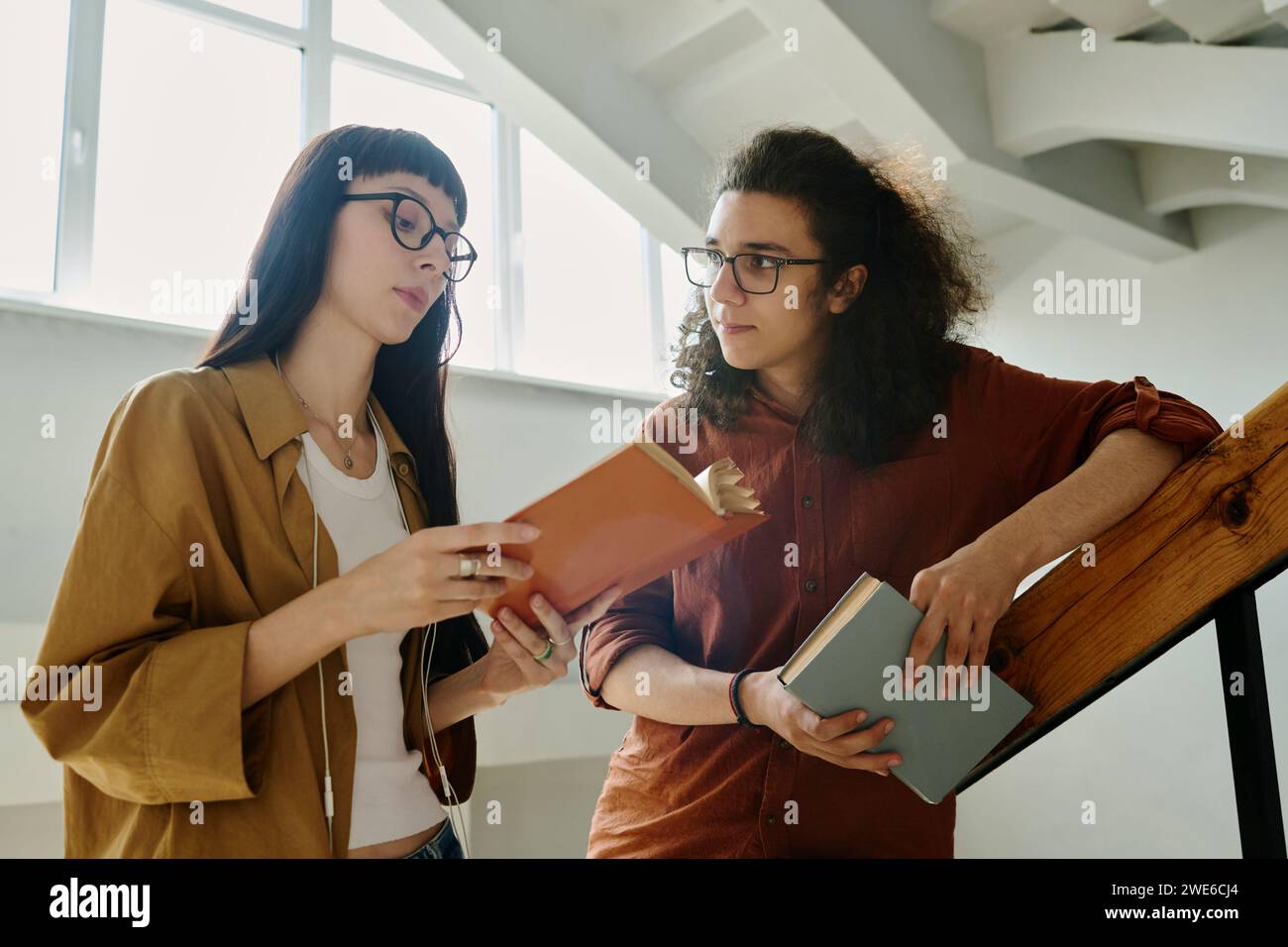 Friends having discussion over book at staircase Stock Photo - Alamy