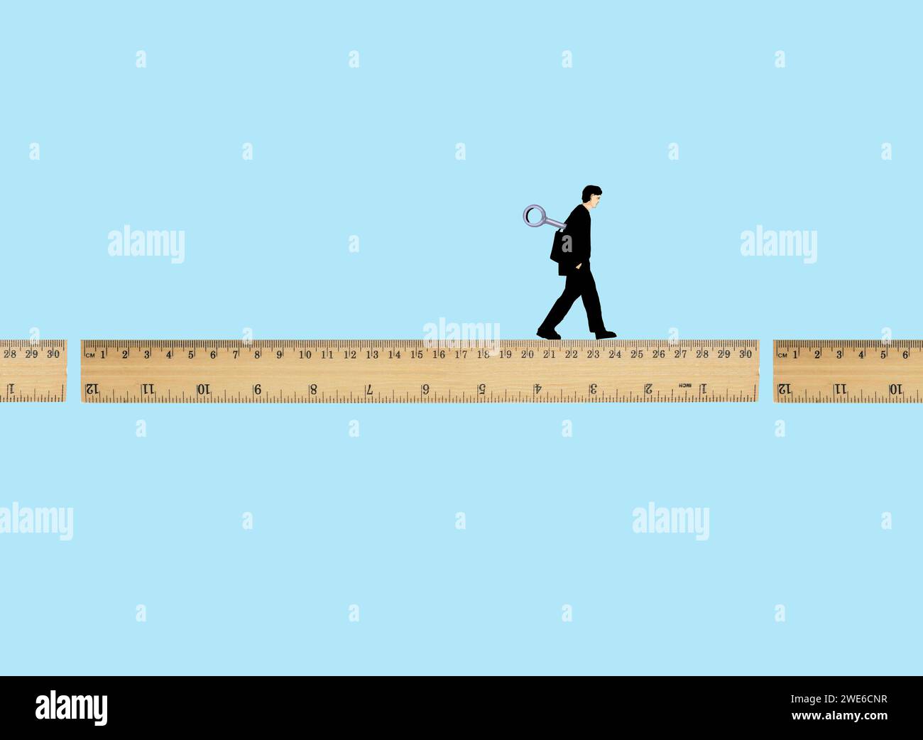 Man walking on broken ruler with wind-up key against blue background ...