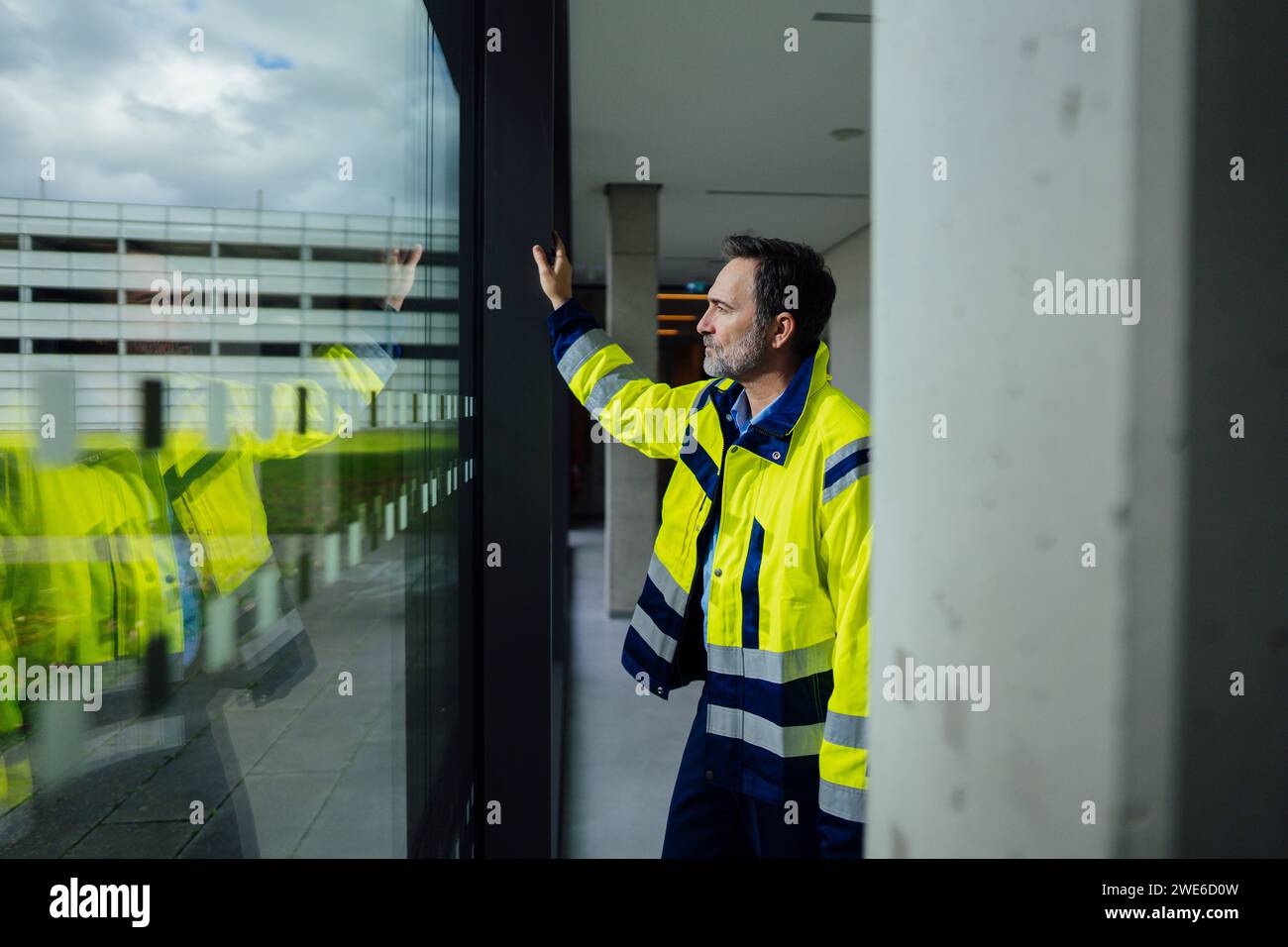 Thoughtful engineer standing near glass window in office corridor Stock ...