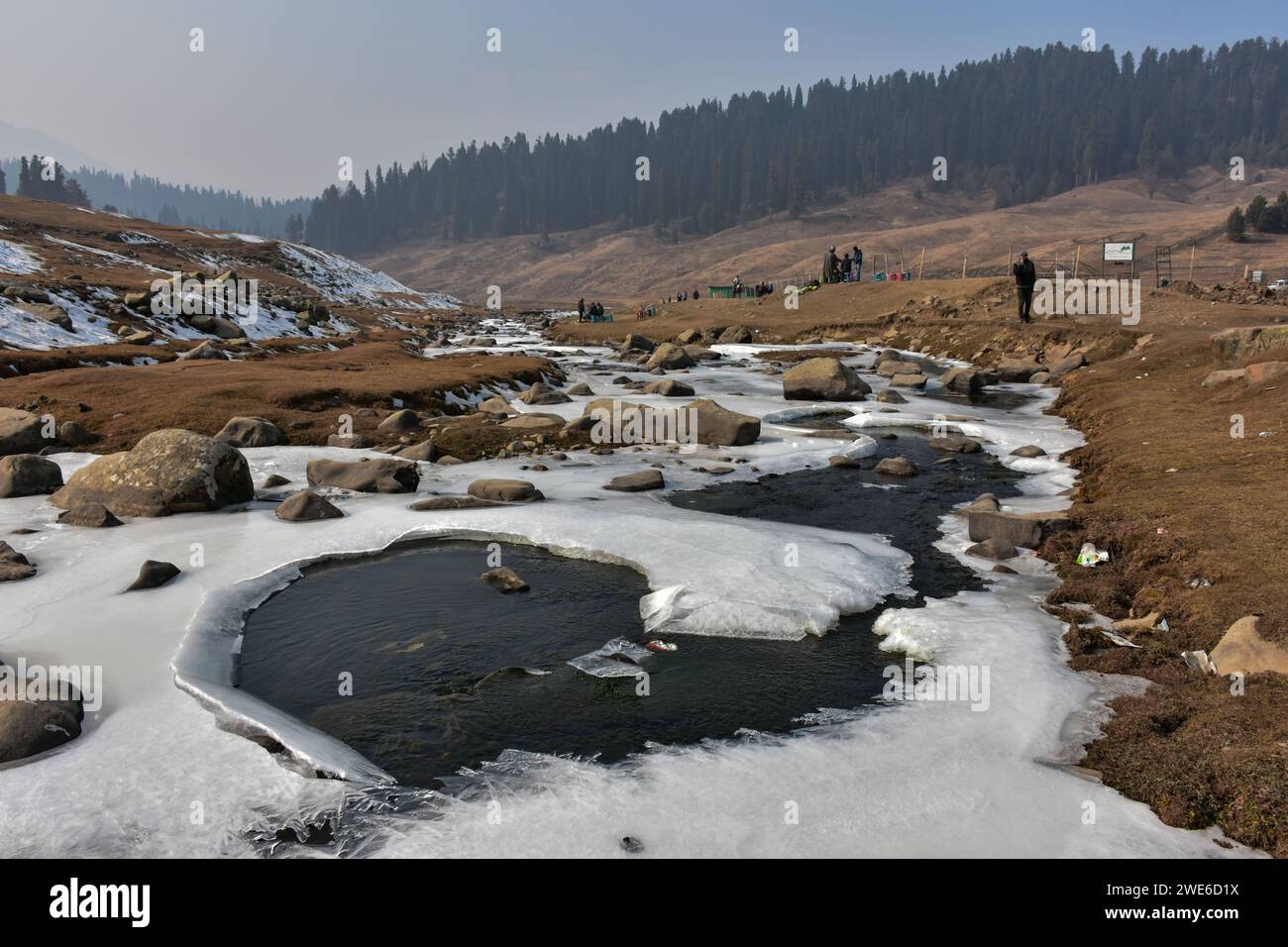 Gulmarg, India. 23rd Jan, 2024. Visitors walk near the frozen stream at ...