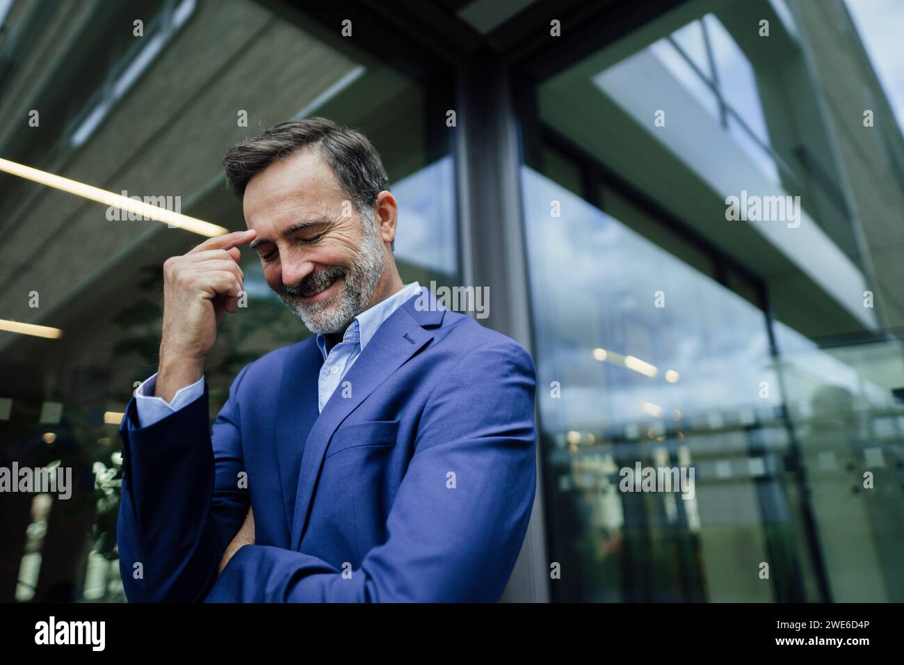 Smiling businessman touching forehead with finger in office Stock Photo ...