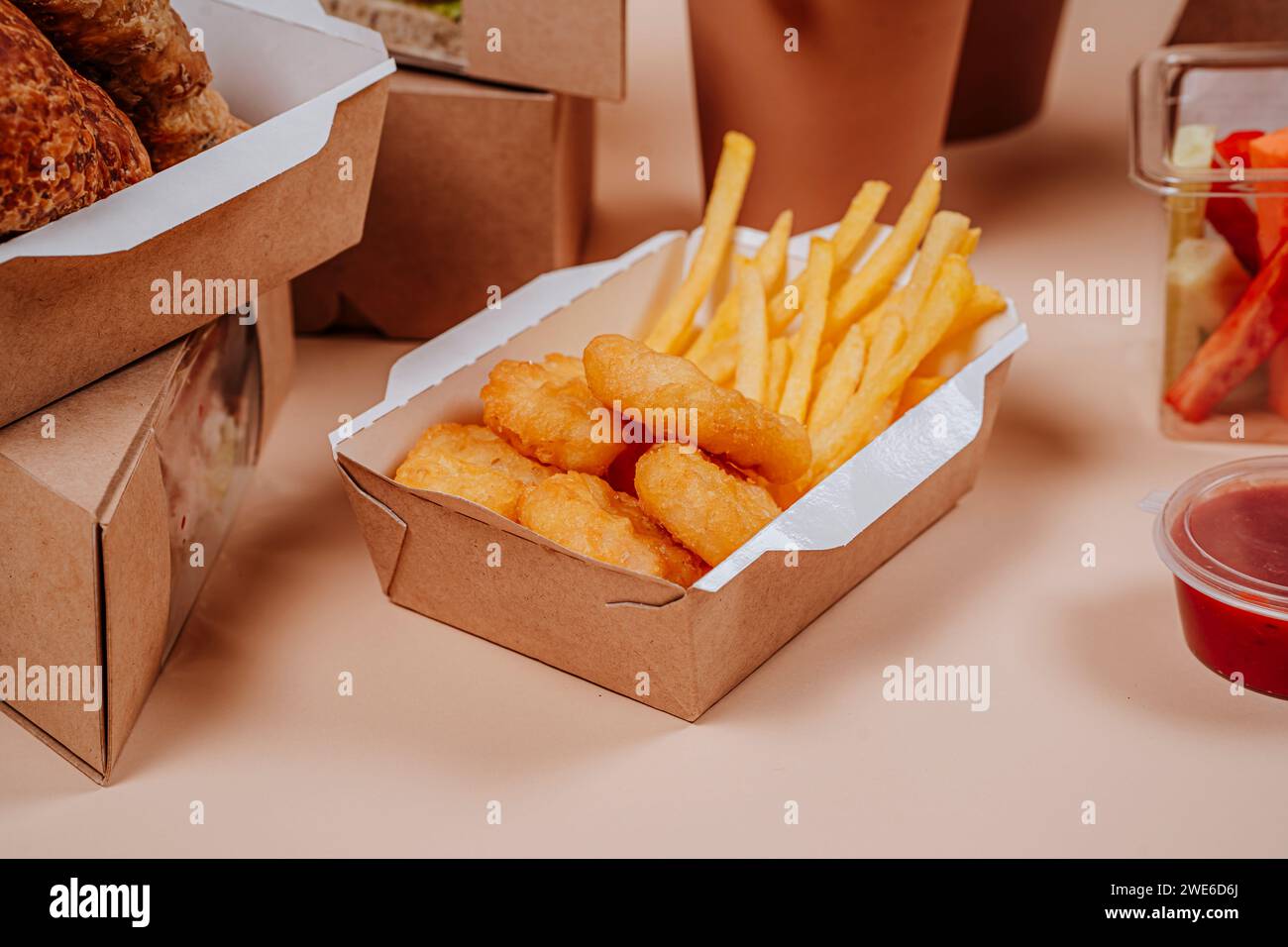French fries and chicken nuggets in container against beige background ...