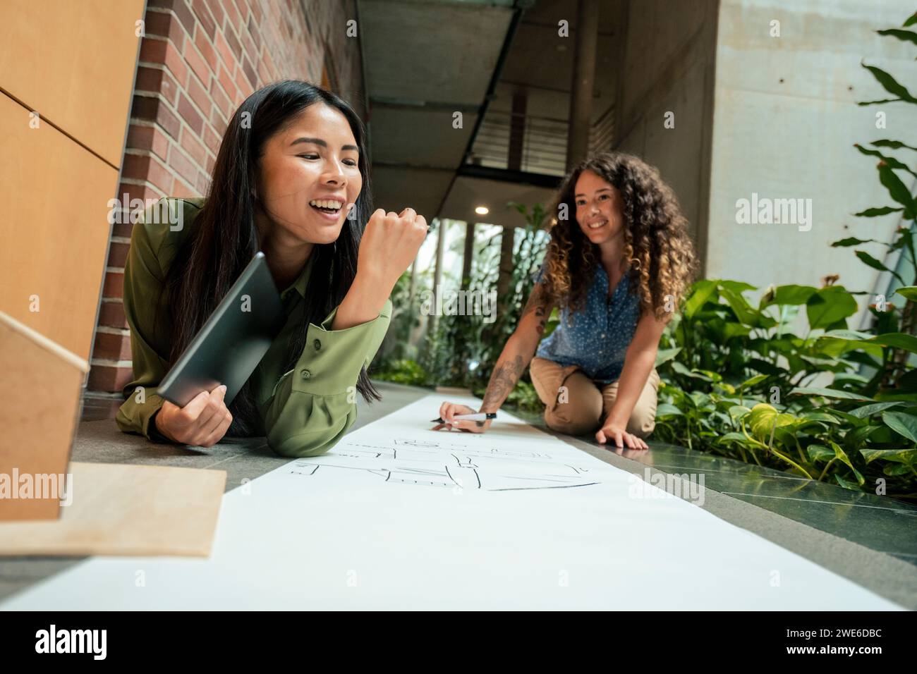 Smiling multiracial architects with blueprint in corridor Stock Photo ...