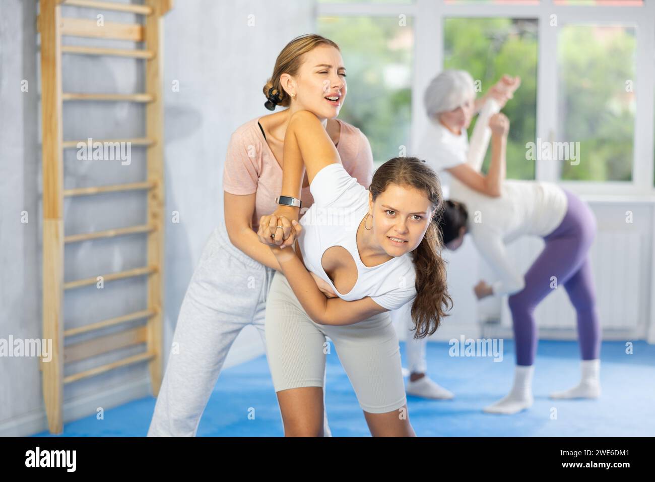 Woman and girl in gym perform basic elements of krav maga self-defense ...