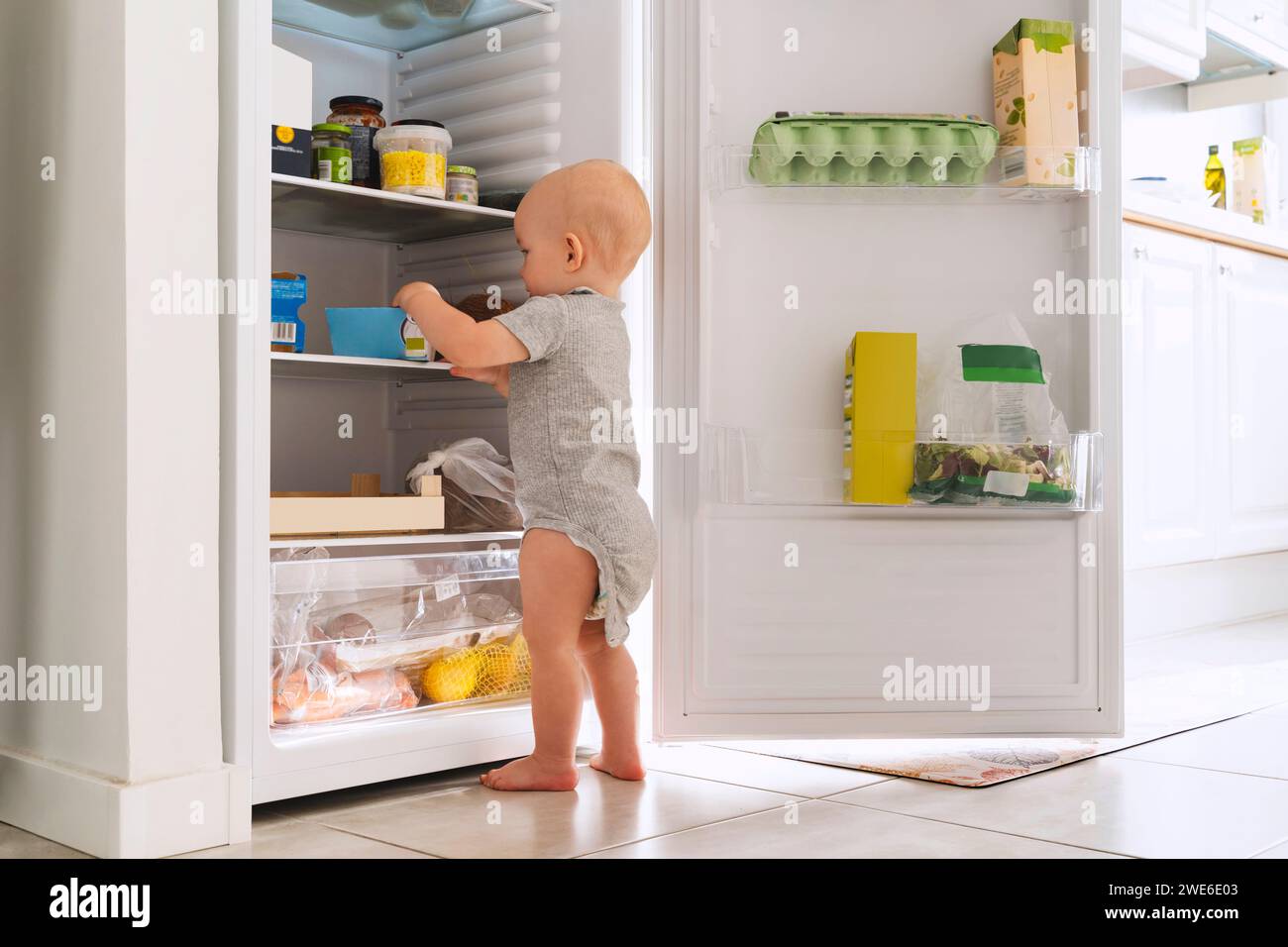 Baby boy exploring food in refrigerator at home Stock Photo - Alamy