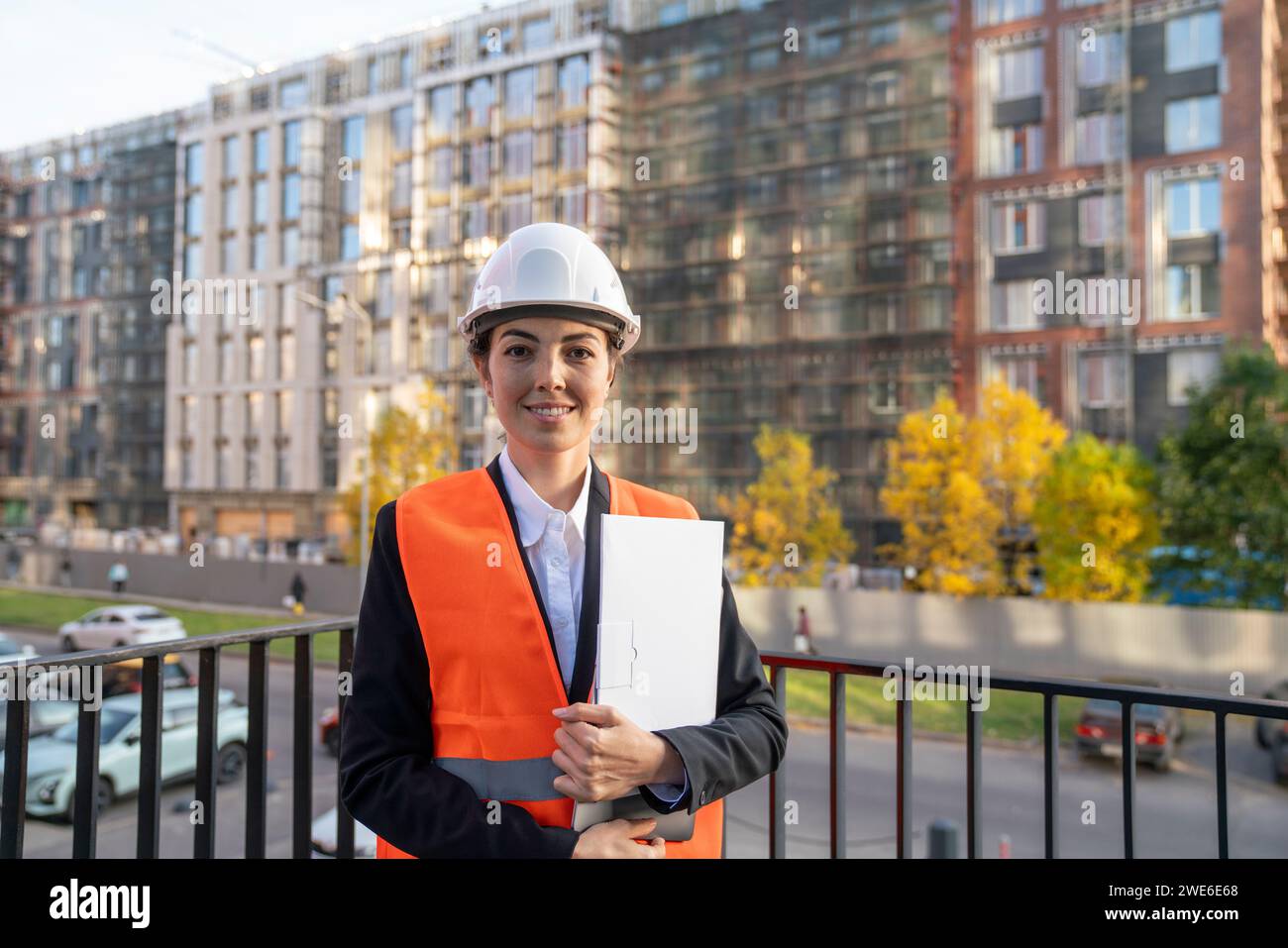 Smiling engineer holding file folder and standing in balcony Stock ...