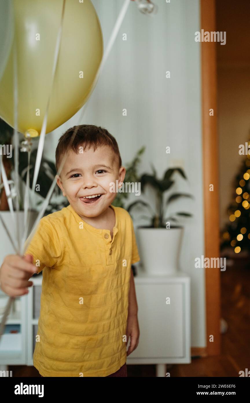 Birthday boy holding balloons at home Stock Photo - Alamy
