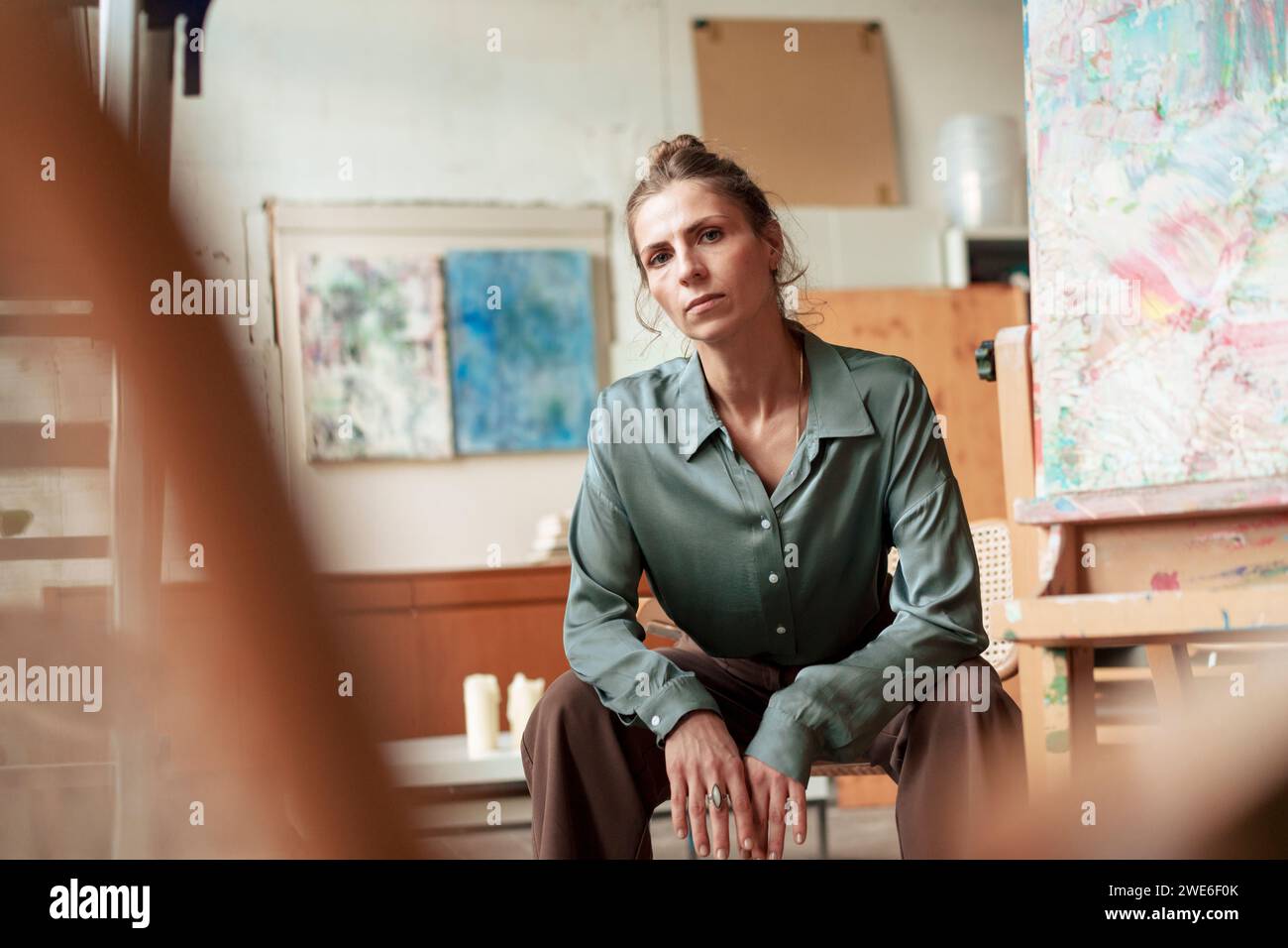 Confident painter sitting on chair in art studio Stock Photo - Alamy