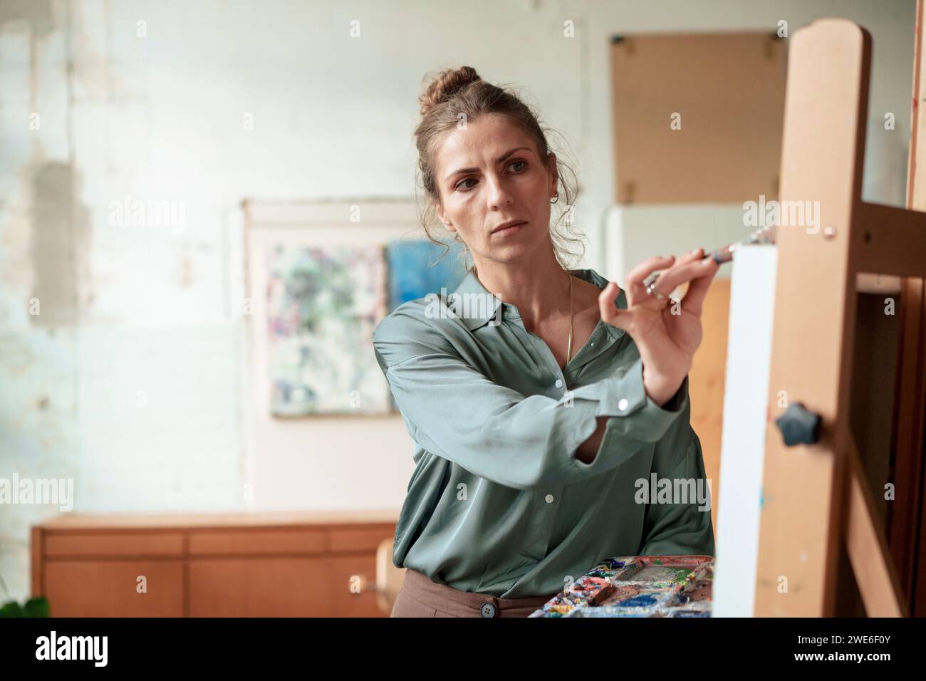 Confident painter painting on easel at art workshop Stock Photo - Alamy