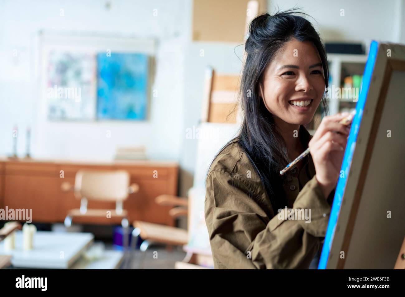 Smiling painter painting on canvas in art studio Stock Photo - Alamy