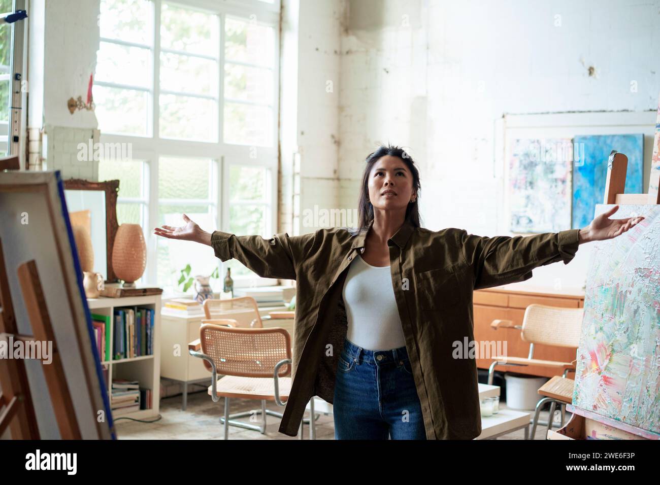 Confident painter standing with arms outstretched in art studio Stock ...