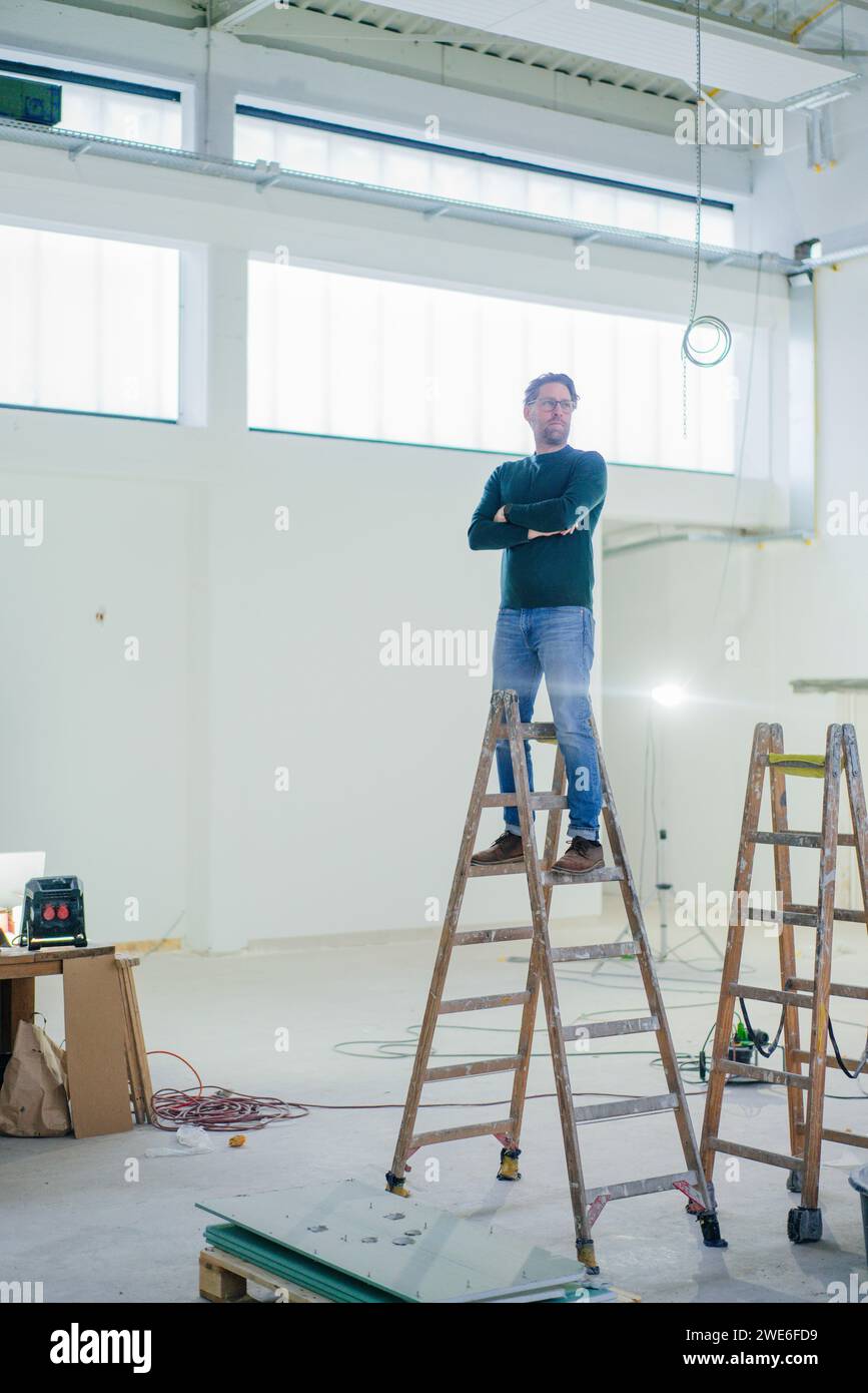 Architect with arms crossed standing on ladder in workshop Stock Photo ...
