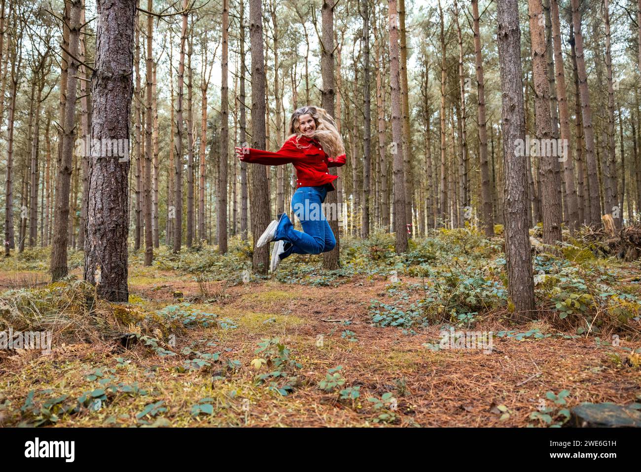 Cheerful woman jumping near trees in Cannock chase forest Stock Photo ...