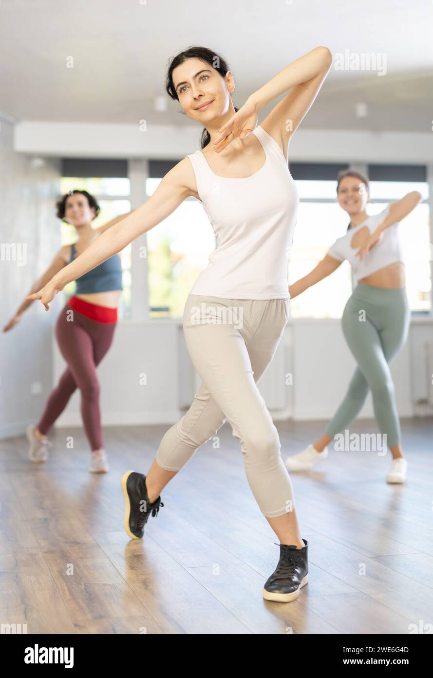 Young female teacher conducts modern dance lessons for group of girls ...