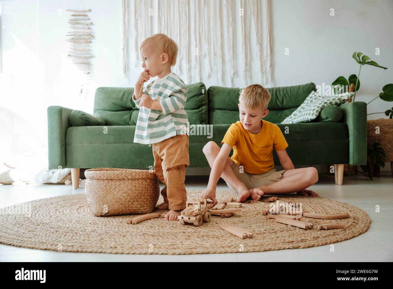 Two brothers playing with wooden train set in living room at home Stock ...