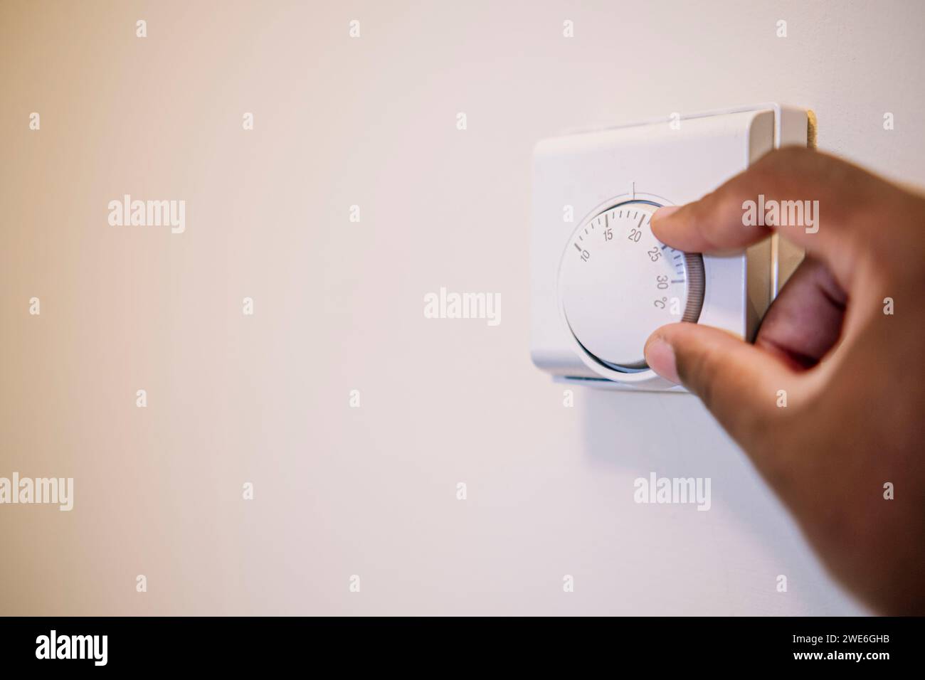 Hand of man adjusting temperature of thermostat at home Stock Photo - Alamy