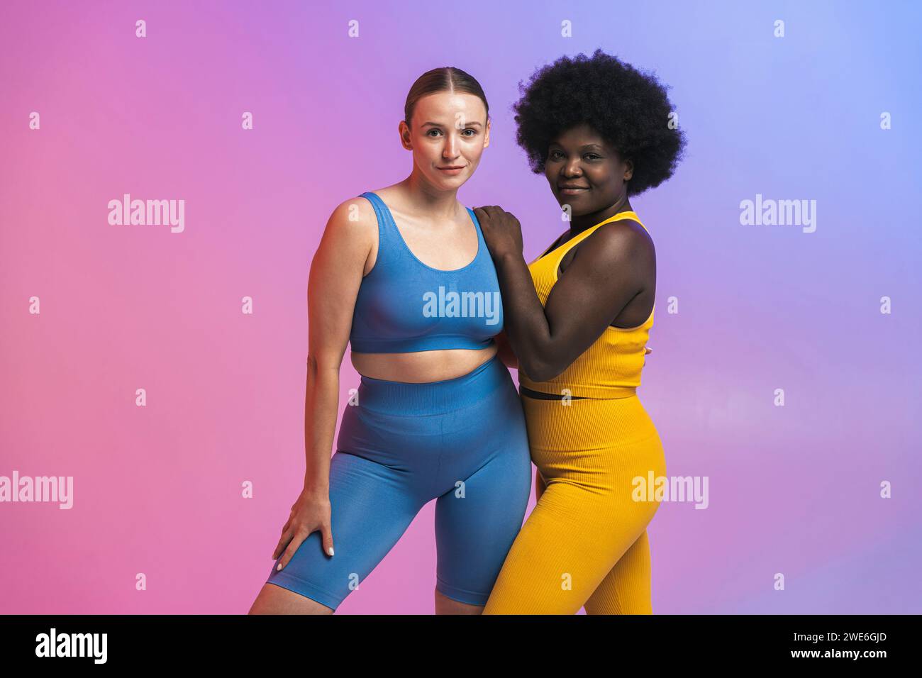 Smiling young woman with Afro hairstyle standing by female friend ...