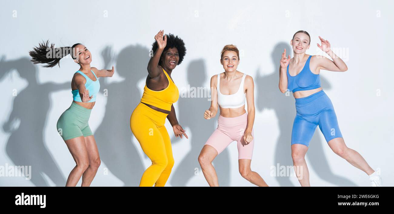 Excited multiracial female friends dancing together against white ...