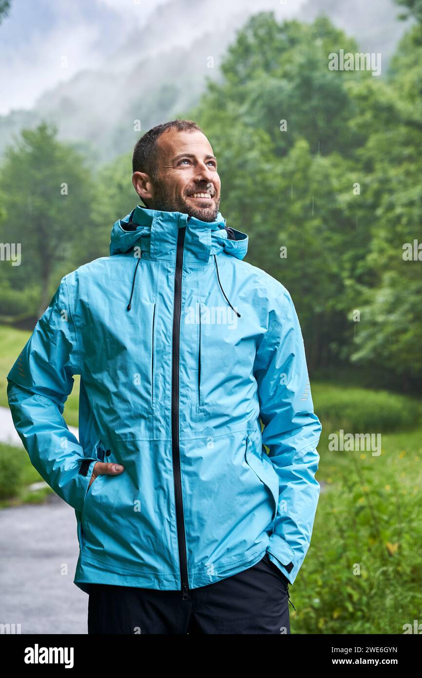 Smiling man wearing blue jacket and standing with hands in pockets on ...