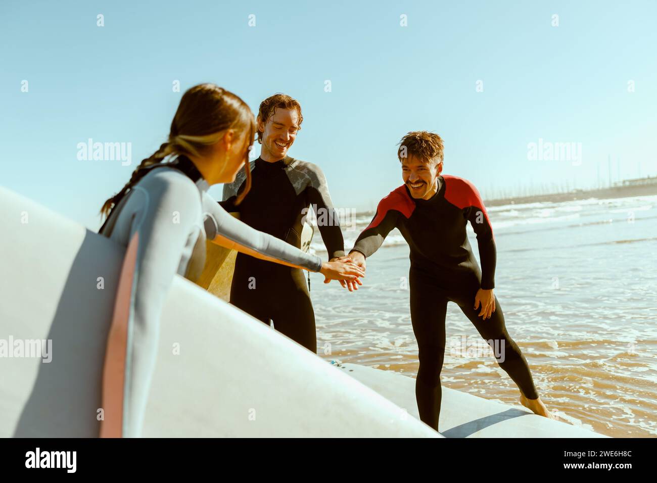 Group of surfers greet each other by shaking hands before surfing on ...