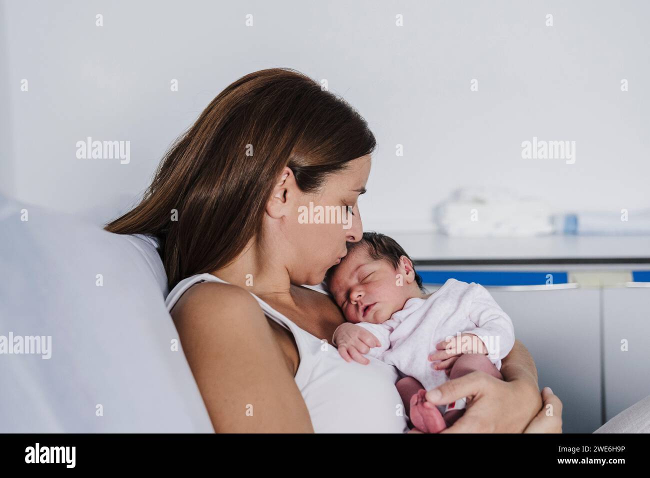 Mother kissing baby daughter on forehead in hospital Stock Photo - Alamy