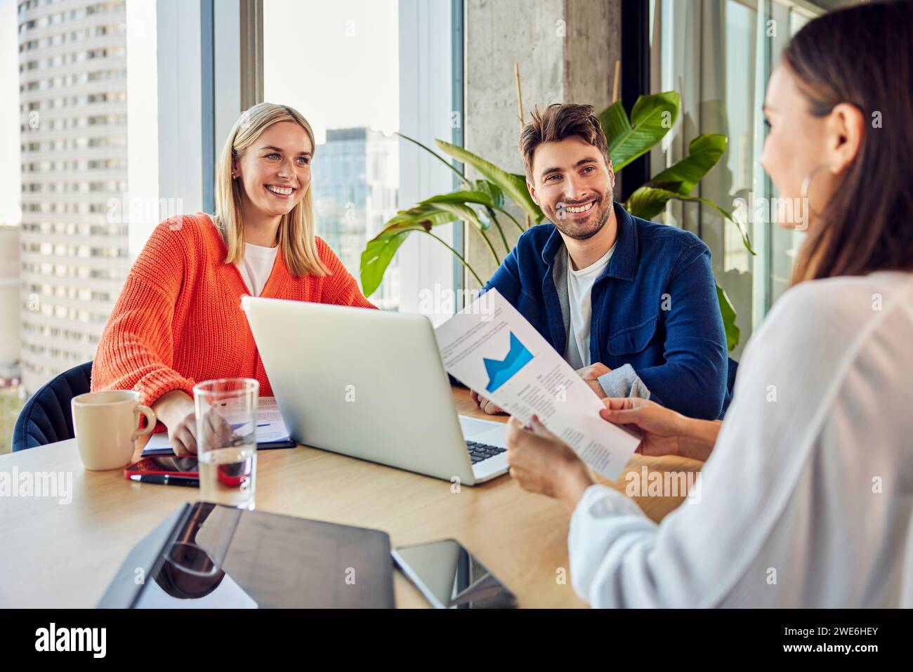 Happy businesswomen and businessman discussing over graph in office ...