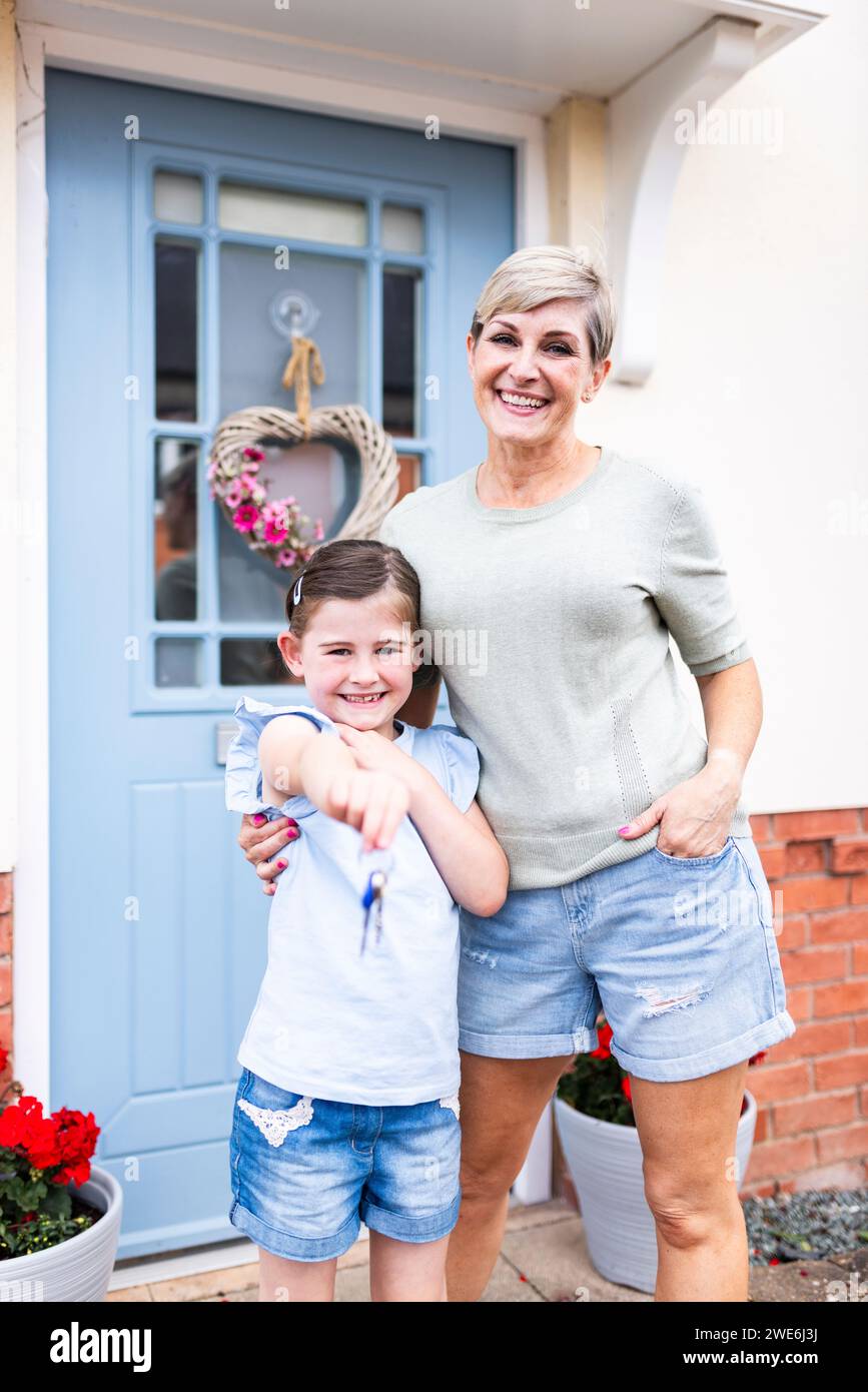 Happy woman with daughter showing keys standing in front of house Stock ...