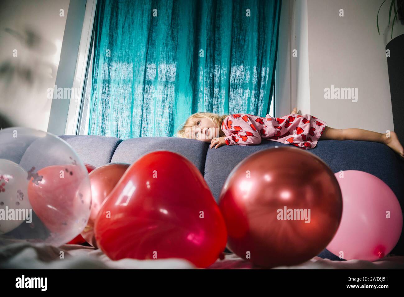 Girl lying on sofa with balloons at home Stock Photo - Alamy