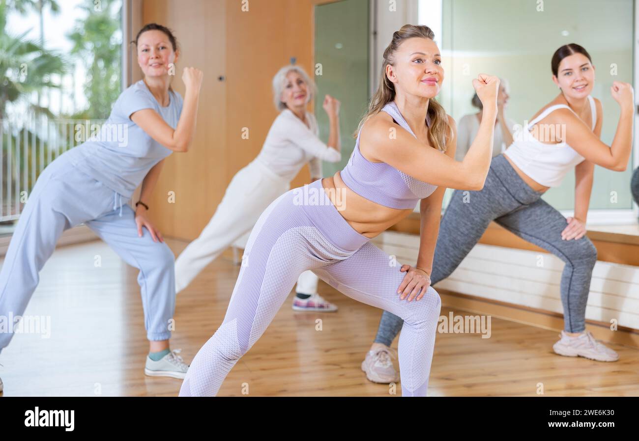 Happy flexible women of different ages exercising active dance with ...