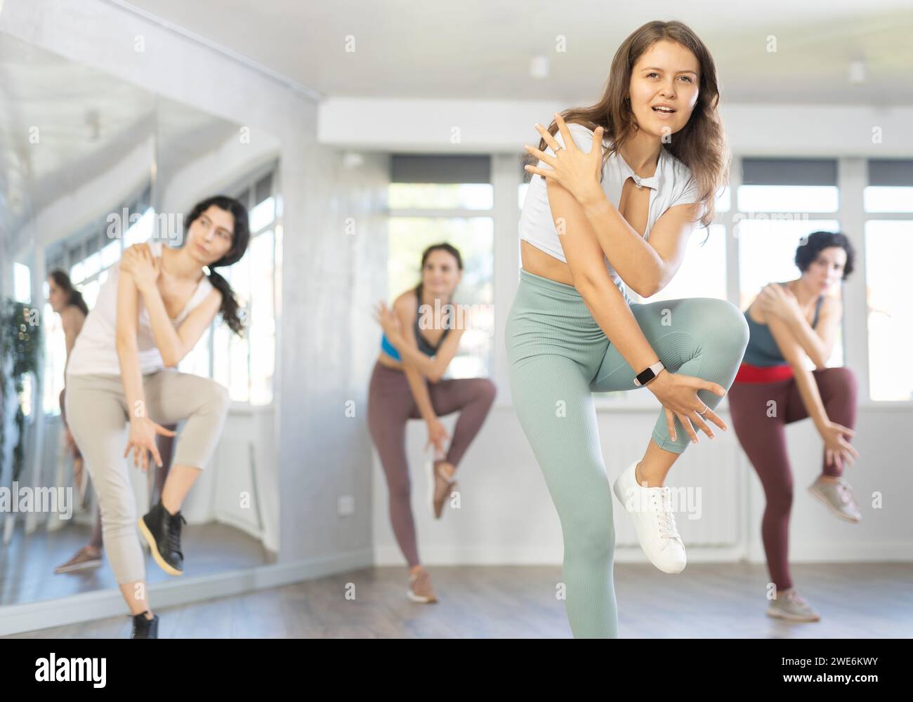 Young female teacher conducts modern dance lessons for group of girls ...