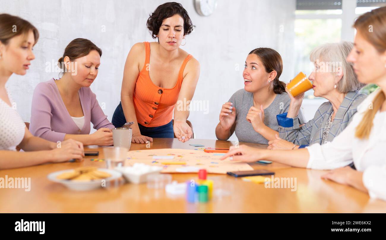 Group of cheerful female colleagues playing board game in office Stock ...